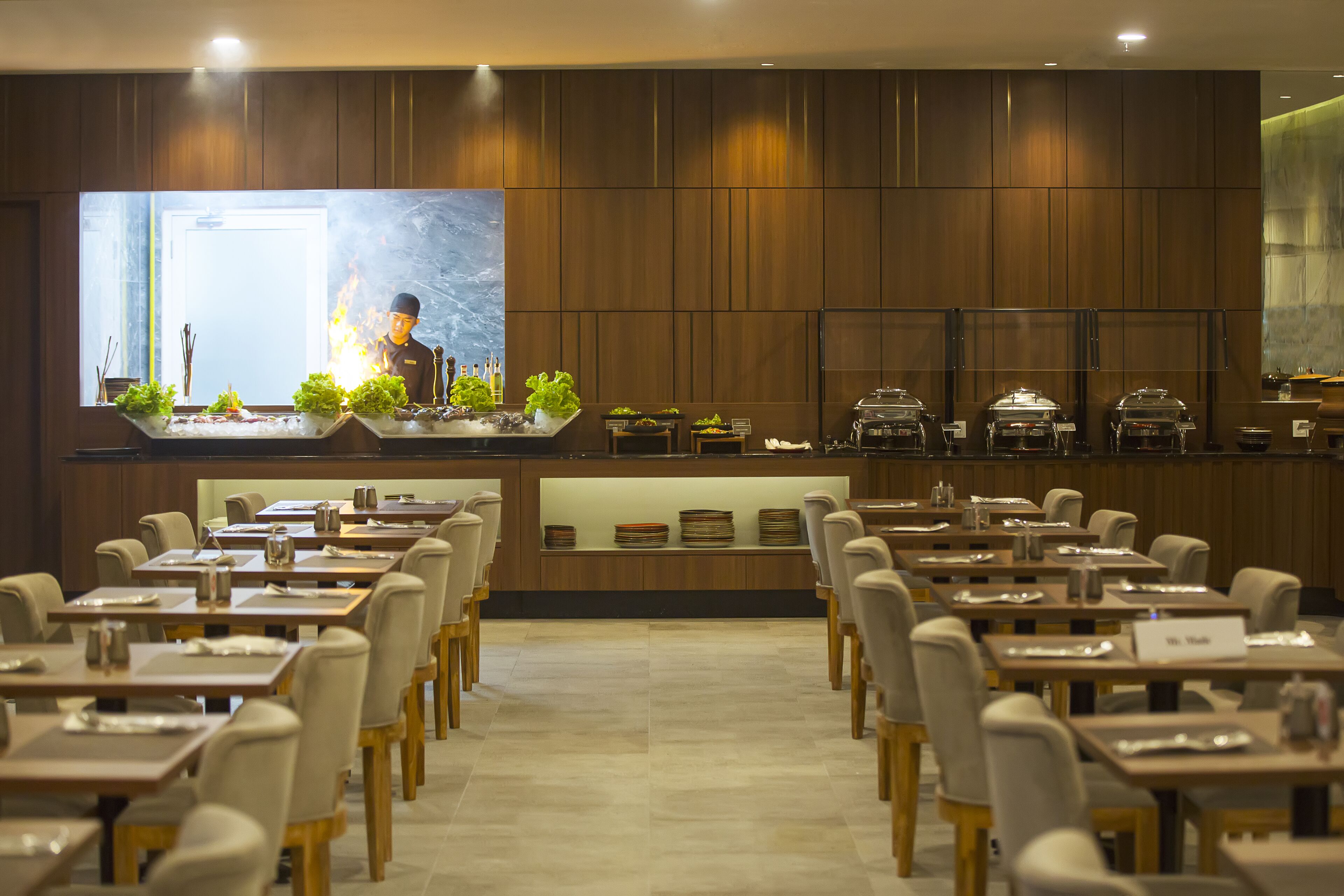 Um restaurante com um balcão extenso, várias mesas e cadeiras.