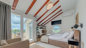 Quarto moderno com uma cama grande, uma escrivaninha e vista para o exterior.