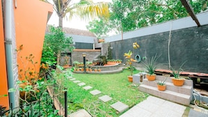 Um pátio com um pequeno jardim, escadas para uma área de estar e uma parede com um mural.