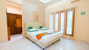Quarto de hotel com cama, guarda-roupa, janela com persianas e um aviso na parede.