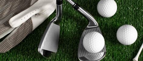 Jogo de tacos de golfe sobre um campo verde, com bolas de golfe e uma bolsa de golfe.