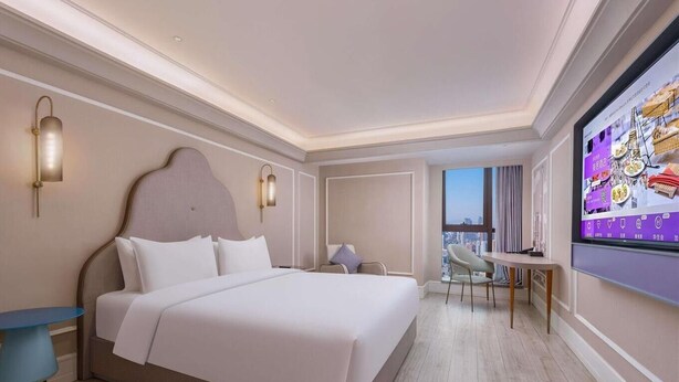 Quarto de hotel com uma cama grande, uma mesa, uma cadeira e uma televisão.
