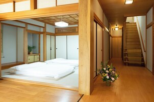 Um quarto tradicional japonês com tatames, futon, armário de madeira e uma pequena mesa com uma planta.
