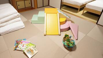 Quarto com duas camas, um armário pequeno e um espaço de recreação com brinquedos e livros.
