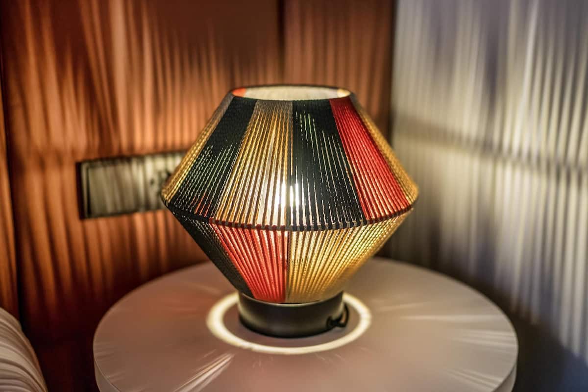 Uma lâmpada com design geométrico sobre uma mesa redonda.