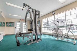 Uma academia com equipamentos de ginástica, uma bicicleta e uma janela grande com vista.