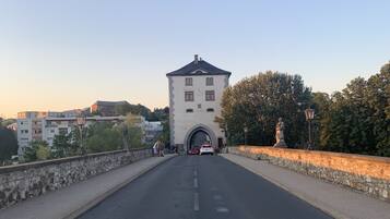 Uma ponte com um muro de pedra de um lado e um edifício com torre do relógio no centro.