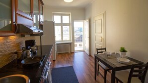 Uma cozinha moderna com armários de madeira, fogão e área de jantar com mesa posta para dois.