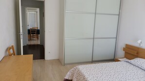Um quarto com uma cama, uma mesa de madeira, uma cadeira e um guarda-roupa.