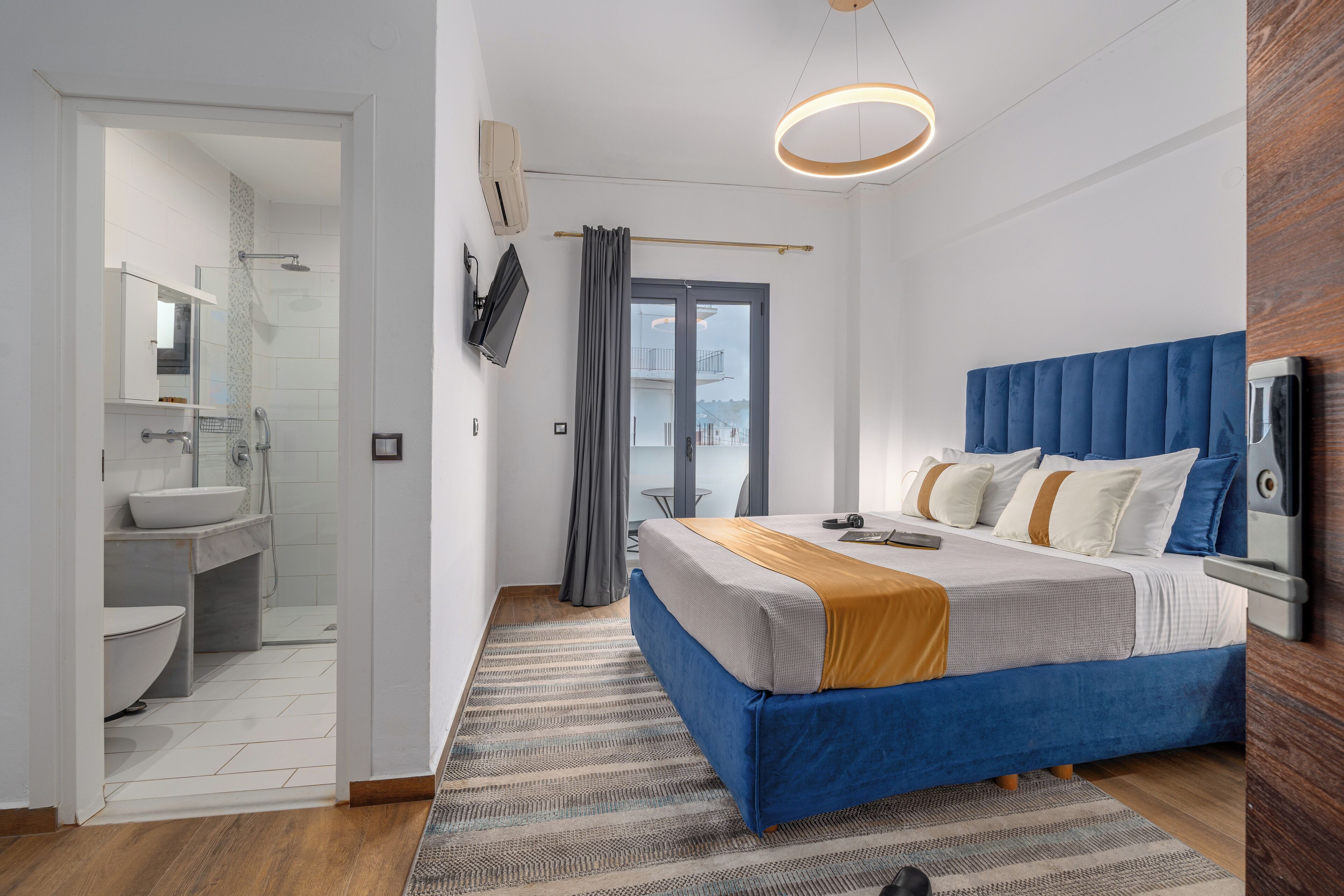 Quarto de hotel moderno com uma cama grande, banheiro com pia e chuveiro, e vista para o exterior.