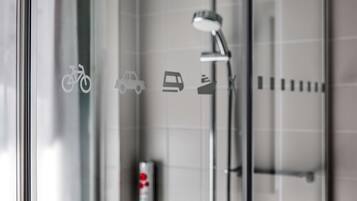 Casa de banho com porta de vidro, chuveiro e painel de comandos com ícones de bicicleta, carro e autocarro.