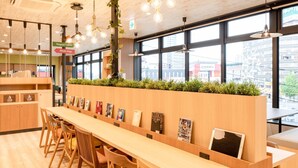 Uma biblioteca moderna com mesas e cadeiras de madeira, estantes e janelas amplas com vista para a cidade.