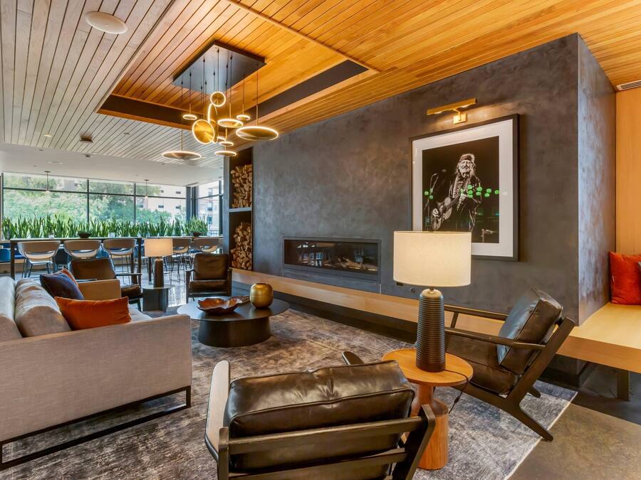 Um interior moderno com um sofá, poltronas de couro, lareira e sala de jantar com cadeiras e mesas.