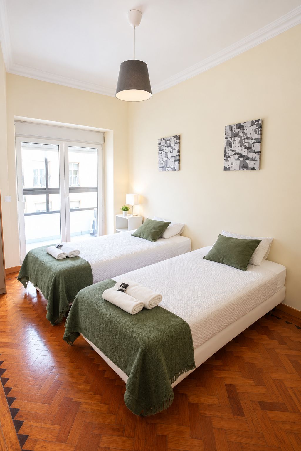 Quarto de hotel com duas camas, uma janela, uma porta e um lustre.