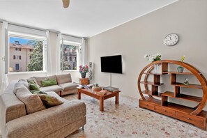 Uma sala de estar com sofá, mesa de centro e um console de madeira com prateleiras.
