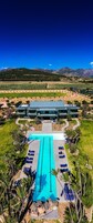 Um hotel moderno com piscina, espreguiçadeiras e vista para as montanhas.