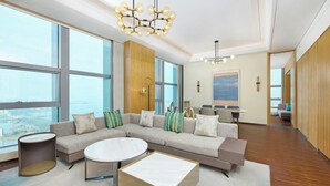 Uma sala de estar moderna com um sofá seccional, uma mesa de centro redonda e uma grande janela com vista para a cidade.