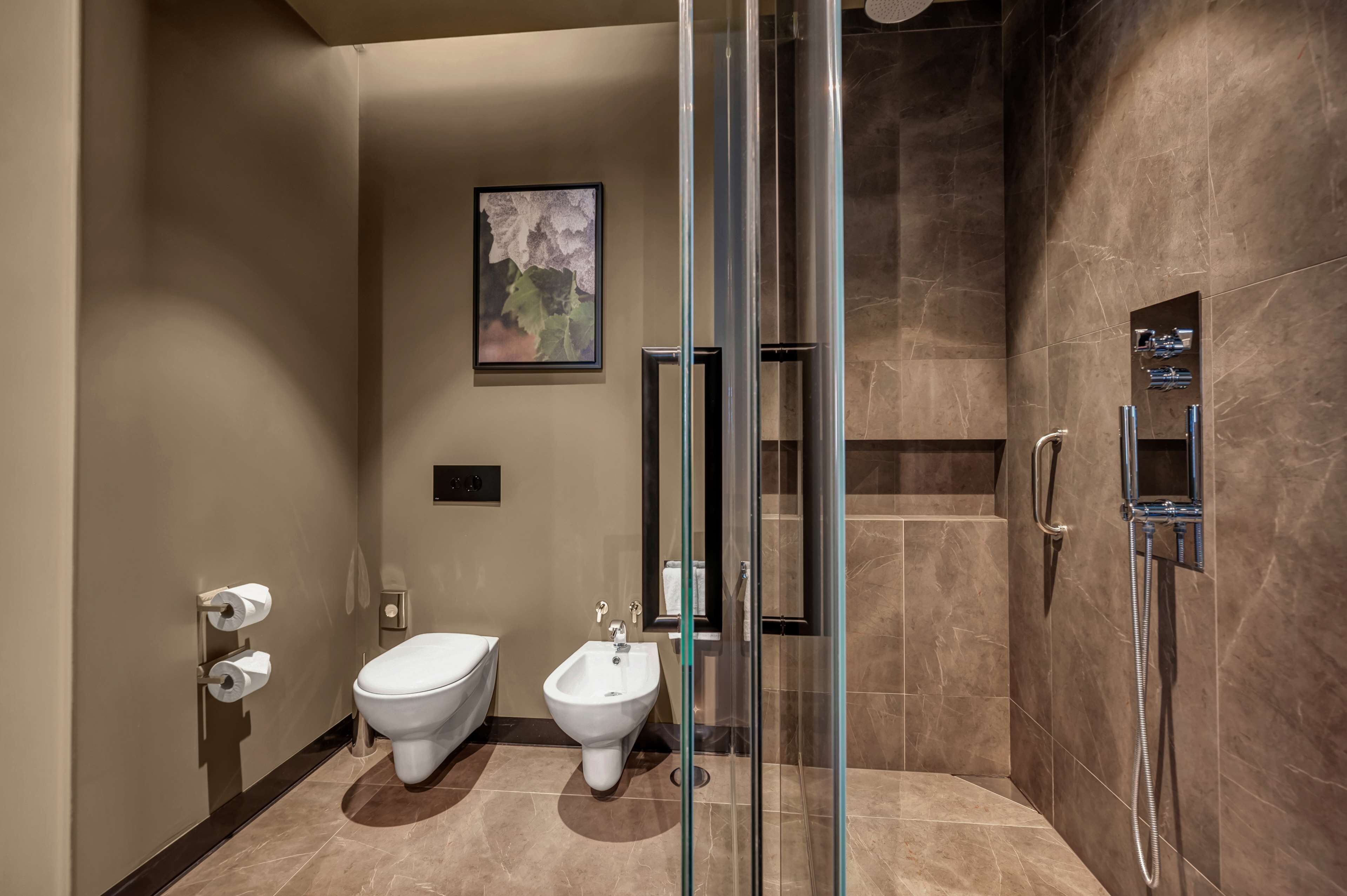Uma casa de banho moderna com bidé, sanita e zona de duche.
