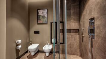 Uma casa de banho moderna com bidé, sanita e zona de duche.