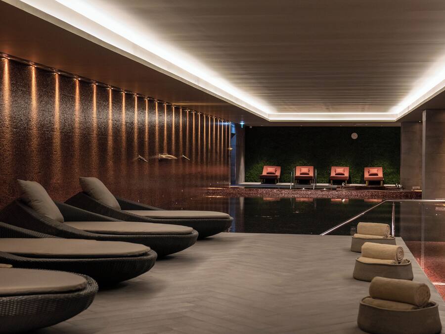 Uma área de spa com parede de tijolos, cadeiras de massagem e piscina.
