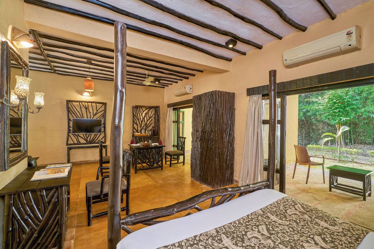Quarto com cama, escrivaninha, televisão e vista para o exterior.
