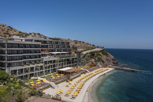 Um hotel à beira-mar com vários andares, área de piscina à beira da praia e um píer que se estende para o mar.