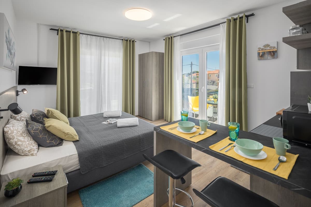Quarto de hotel moderno com cama, escrivaninha e cadeira, televisão e vista para a cidade.
