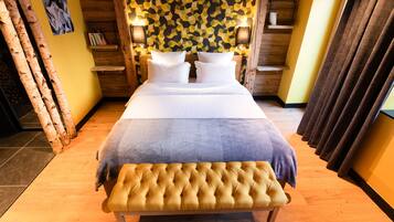 Quarto bem arrumado com uma cama grande, mesas de cabeceira e um banco.
