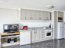Cozinha moderna com armários brancos, lava-louças, micro-ondas e forno embutido.