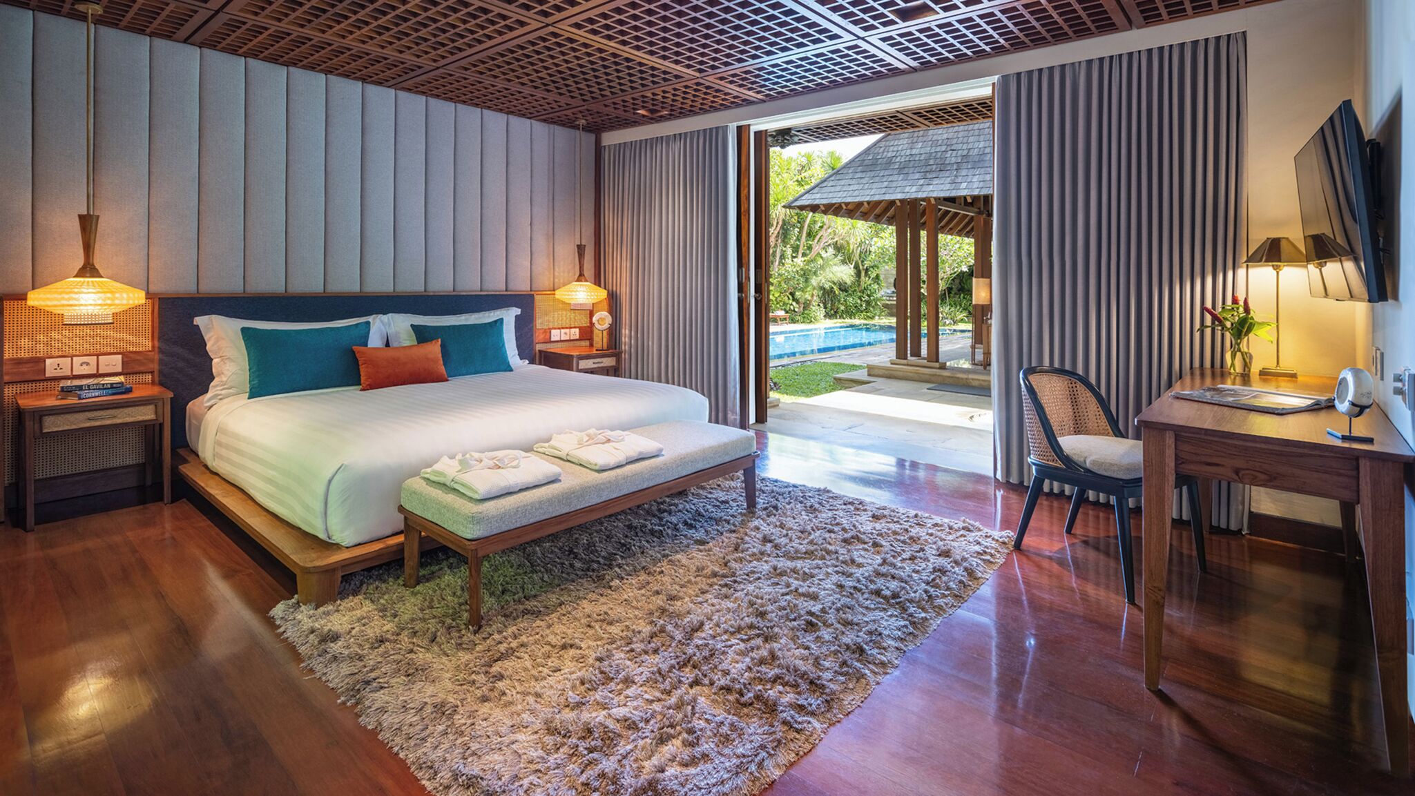 Um quarto espaçoso com uma cama grande, uma escrivaninha e vista para uma piscina.