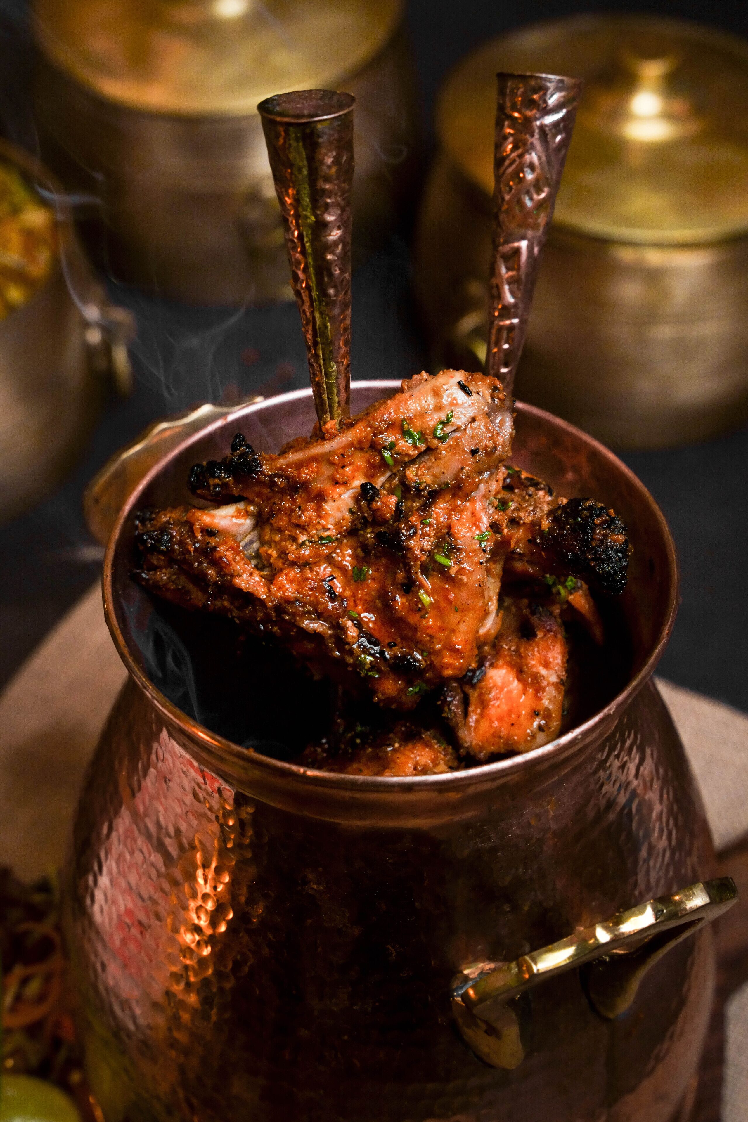 Uma panela de cobre com um pedaço de frango assado, decorada com ervas.
