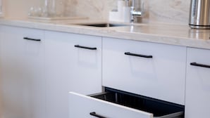 Uma cozinha moderna com armários brancos, painel de fundo de mármore e torneira de aço inoxidável.