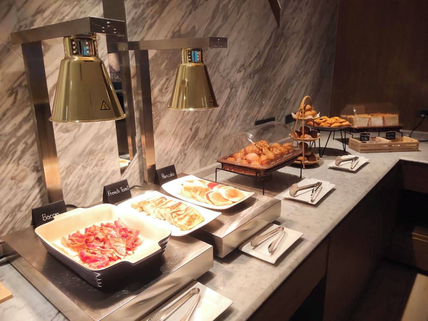 Buffet montado com pratos identificados como 'Fresh Toast', 'Bacon' e 'Panqueca'.