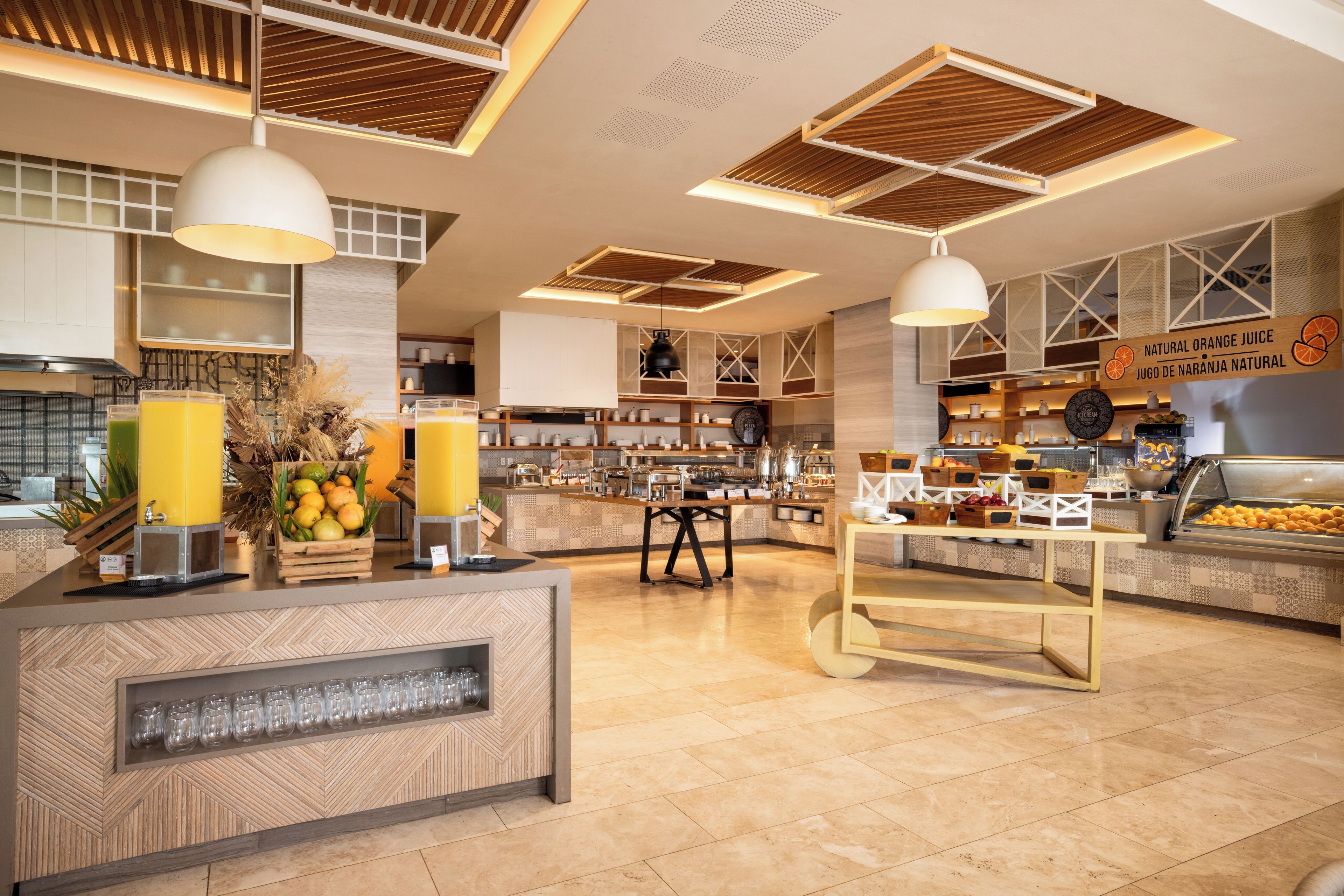 Cozinha moderna com ilha central, iluminação embutida e área de buffet com diversos alimentos.