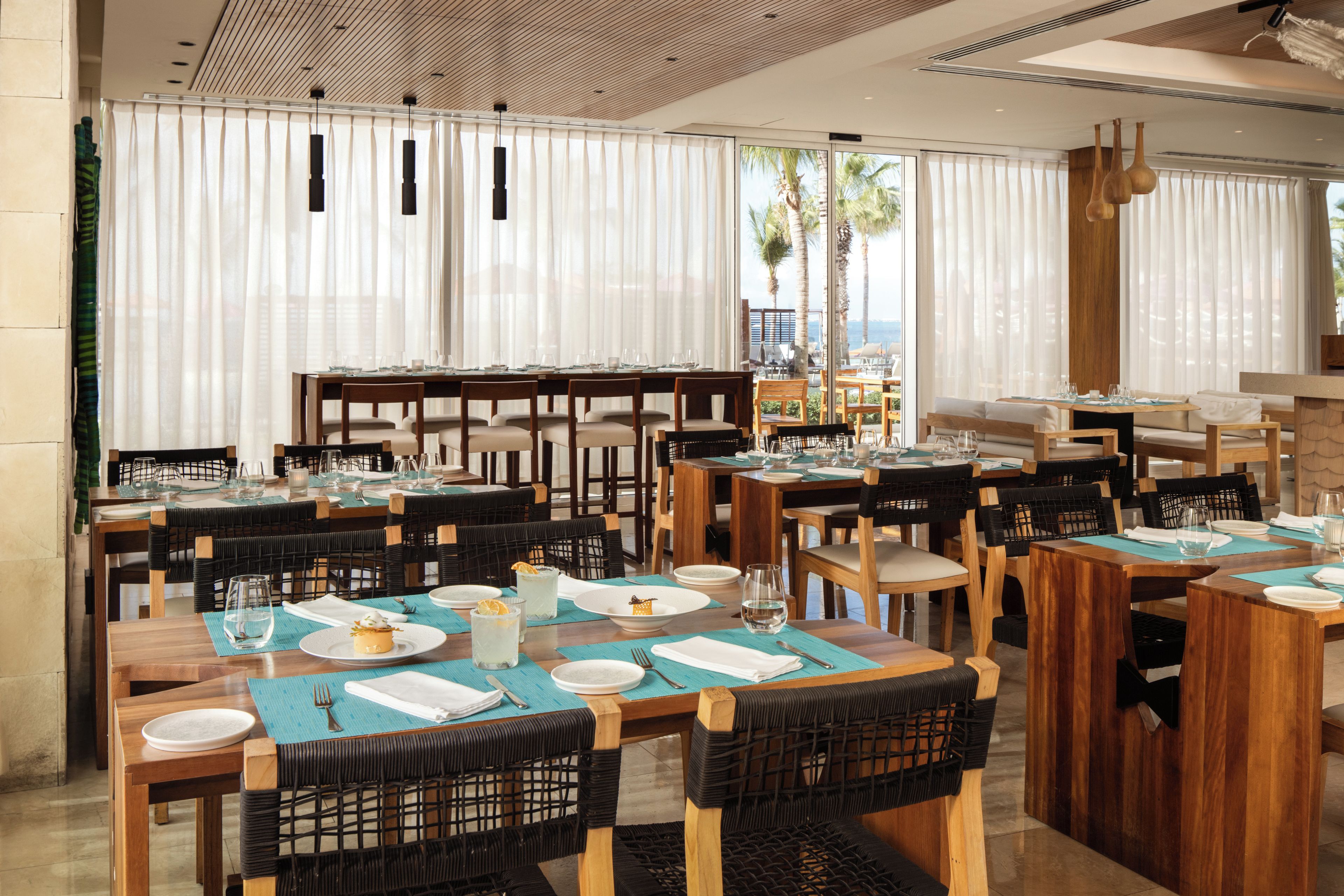 Um restaurante com várias mesas e cadeiras dispostas para refeições.