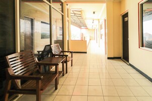 Corredor com bancos de madeira, piso de azulejos e porta com o símbolo de número.