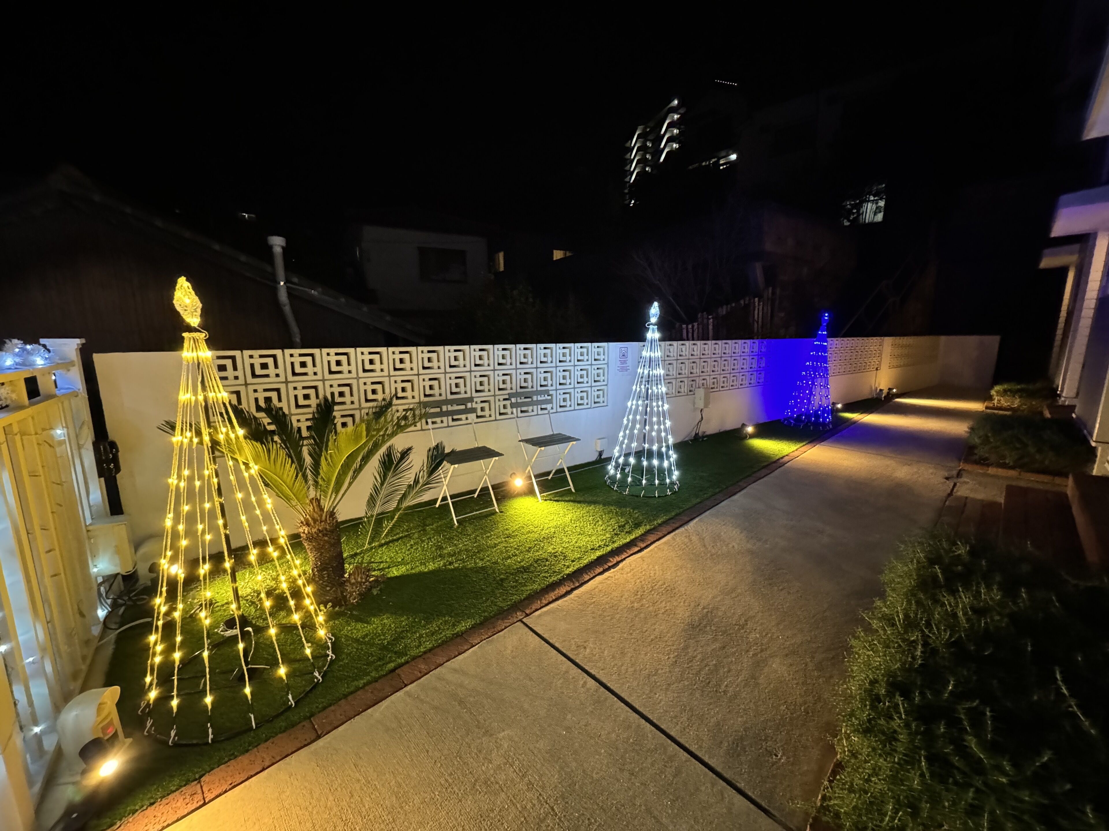 Um caminho ladeado por estruturas de iluminação decorativas e um gramado bem cuidado.