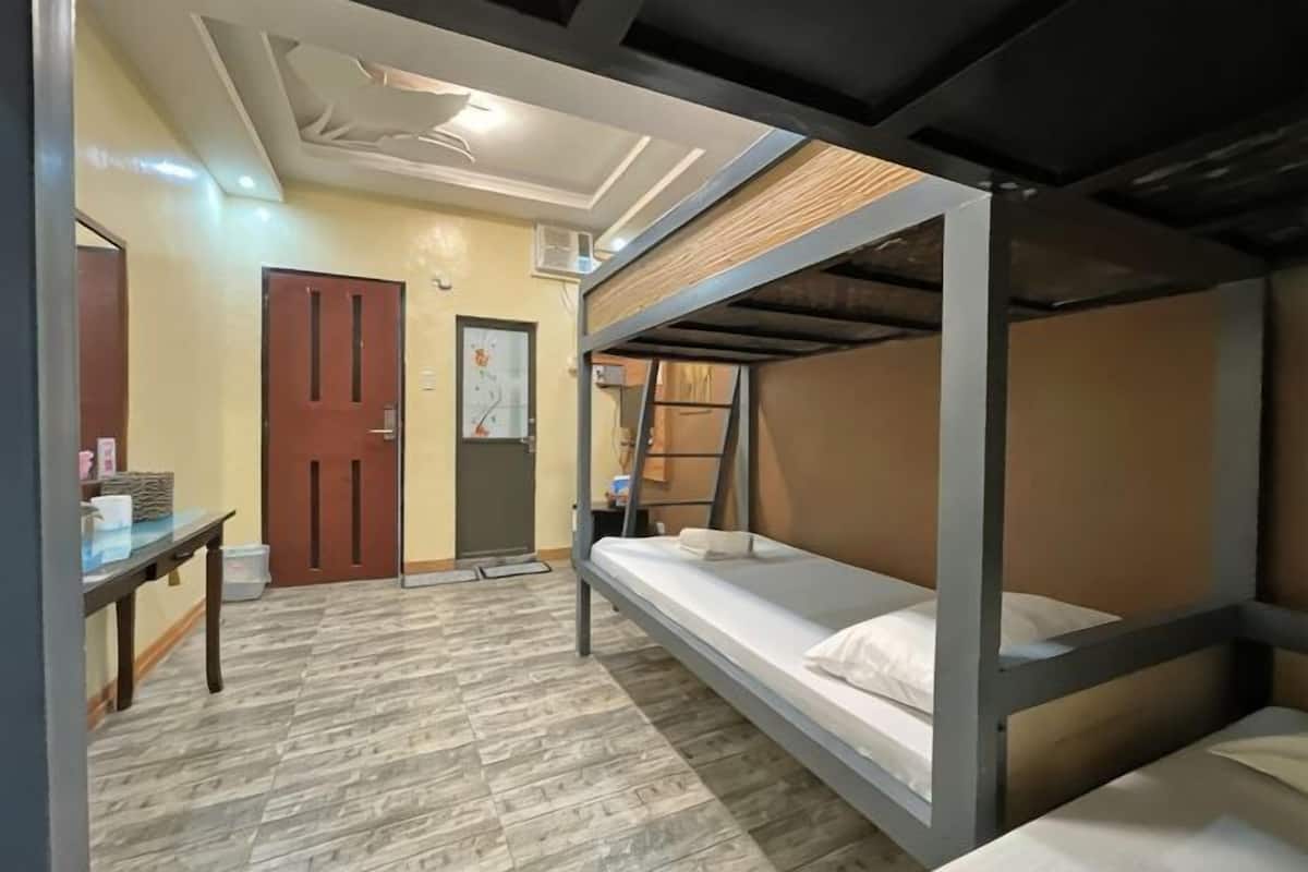 Quarto com beliche, escrivaninha e porta.