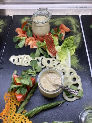 Salada com diversos vegetais e um frasco de molho sobre uma lousa.