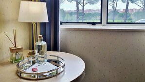Quarto de hotel com uma mesa redonda, uma luminária, uma garrafa de água, um copo e um tabuleiro com um menu.