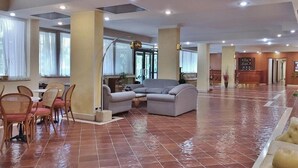 Um hall amplo com área de estar, balcão de recepção e uma janela grande.