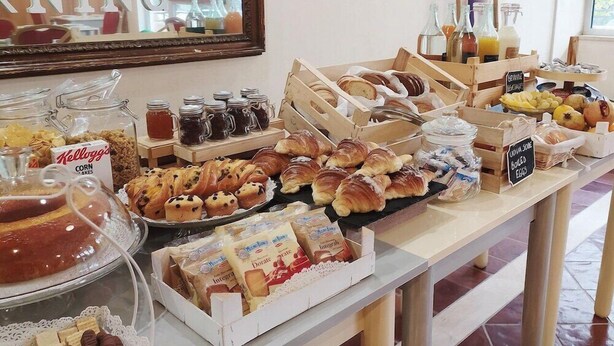 Um buffet de café da manhã com diversos pães, bolos e acompanhamentos.