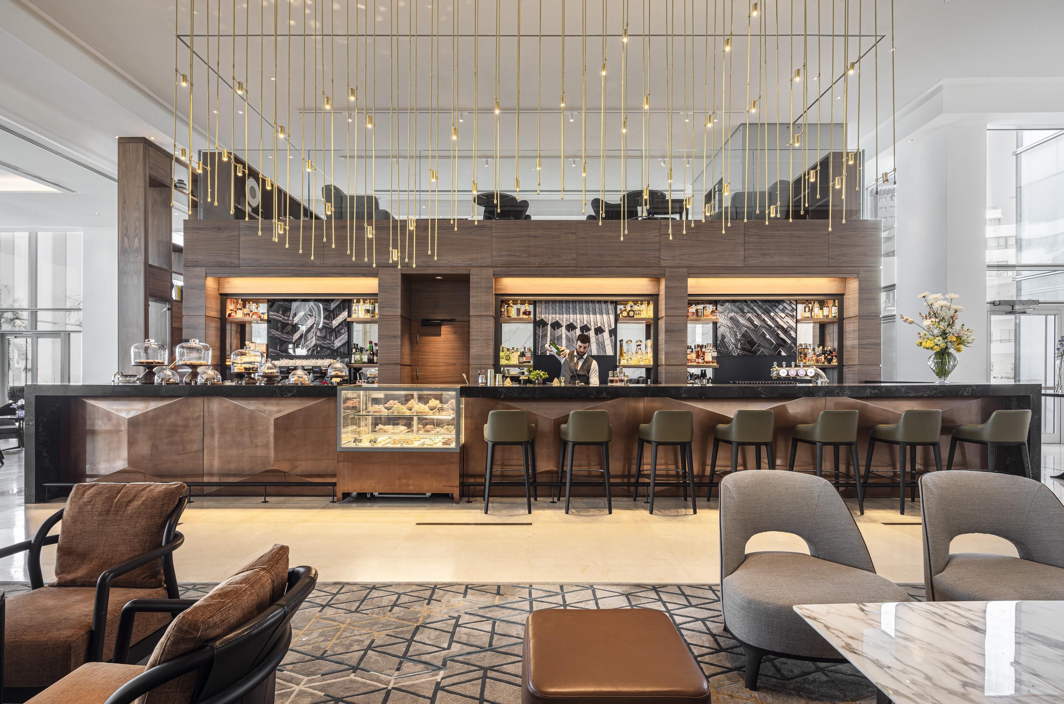 Uma área de bar moderna com balcão, banquetas e um espaço de estar com cadeiras e mesa.
