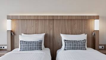 Uma cama de casal com cabeceira de madeira, duas mesas de cabeceira e almofadas estampadas.