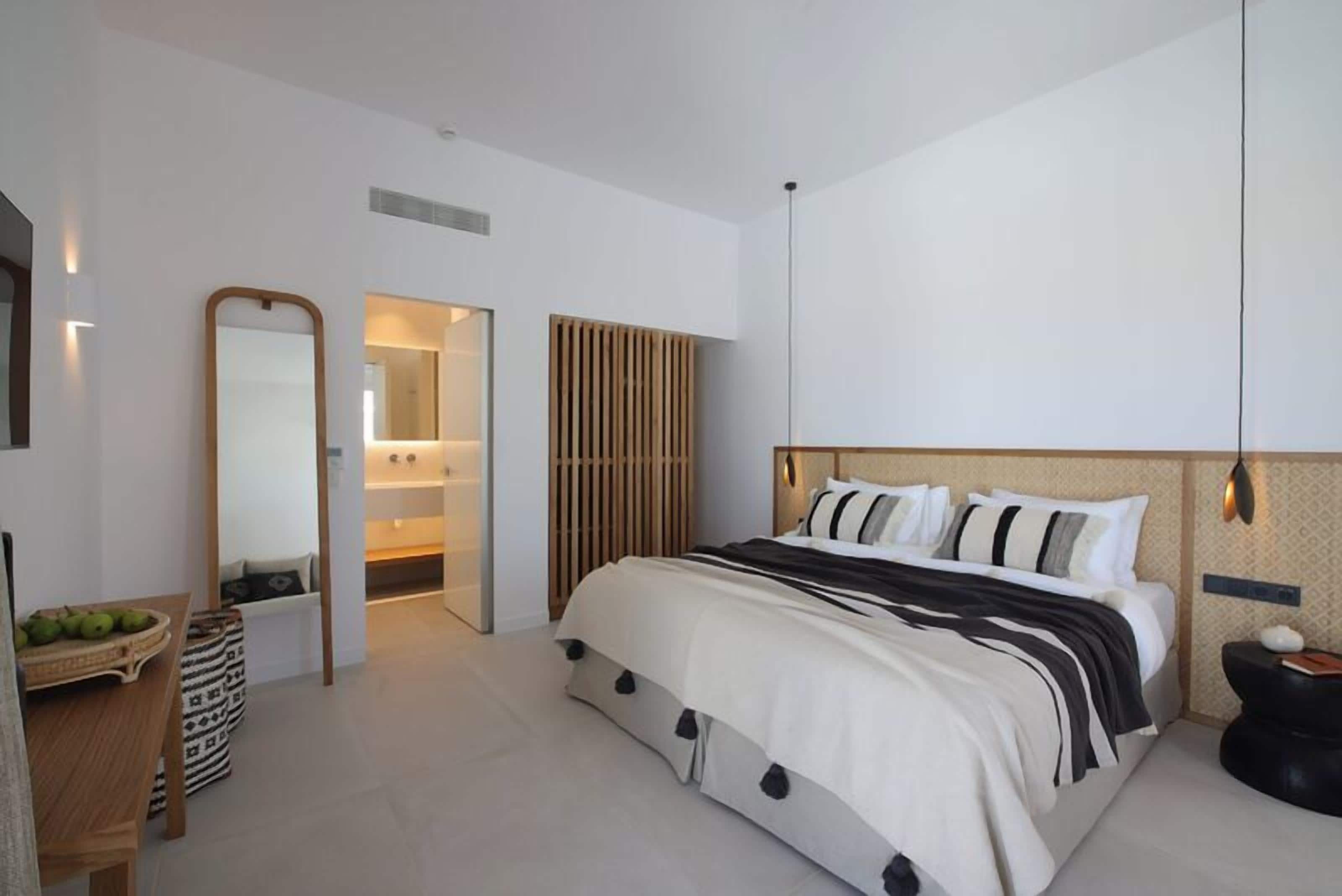 Quarto moderno com cama grande, mesas de cabeceira, guarda-roupa e espelho.