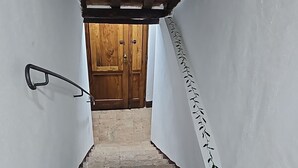 Uma escadaria estreita com degraus de pedra que levam a uma porta de madeira.