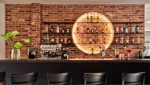 Uma área de bar com parede de tijolos, prateleiras cheias de garrafas de bebidas, uma máquina de café e quatro banquetas.