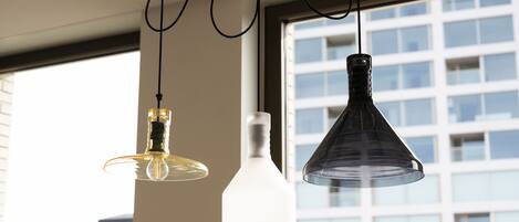 Três luminárias pendentes suspensas no teto de um quarto com uma janela grande.