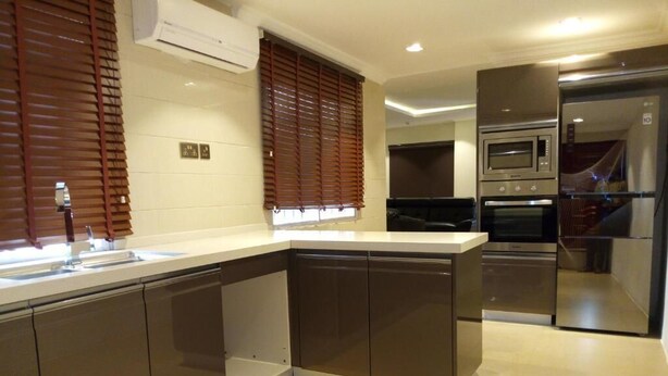 Uma cozinha moderna com armários escuros, uma ilha central e eletrodomésticos embutidos, incluindo micro-ondas e forno.