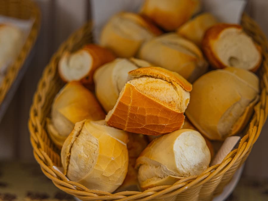 Uma cesta cheia de pães redondos e dourados.